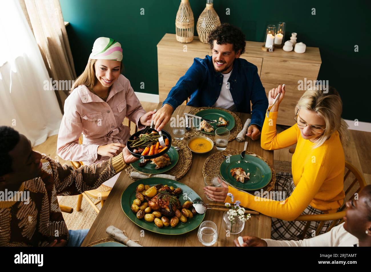 Smiling friends enjoying lunch at dining table in home Stock Photo - Alamy