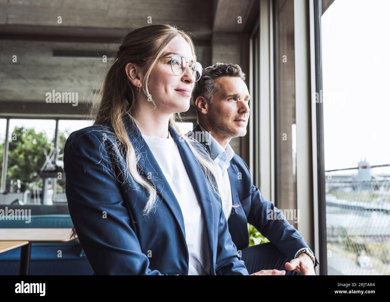 Thoughtful business colleagues looking through window in office Stock ...