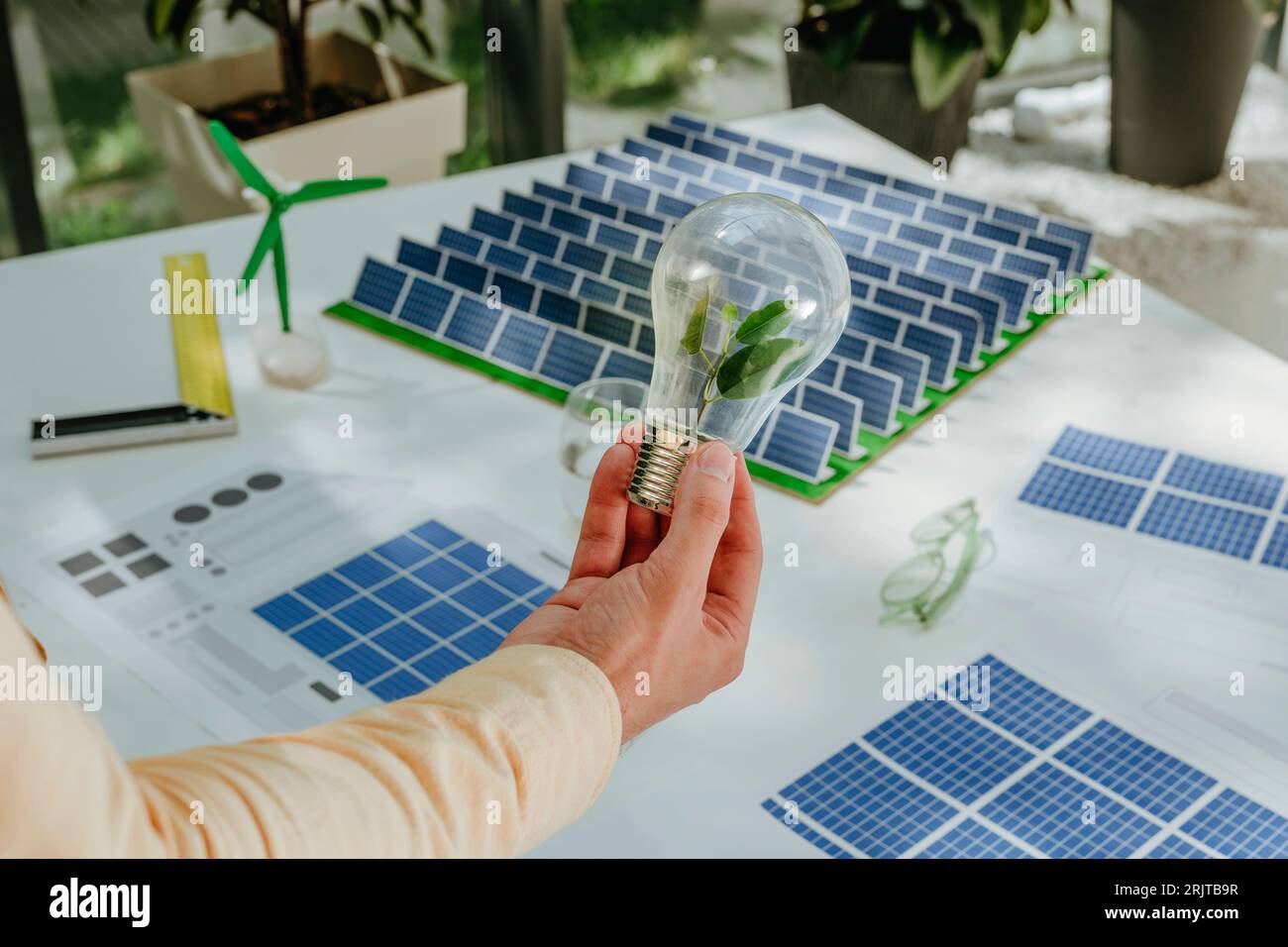 Hand of businessman holding light bulb over solar panels model Stock ...