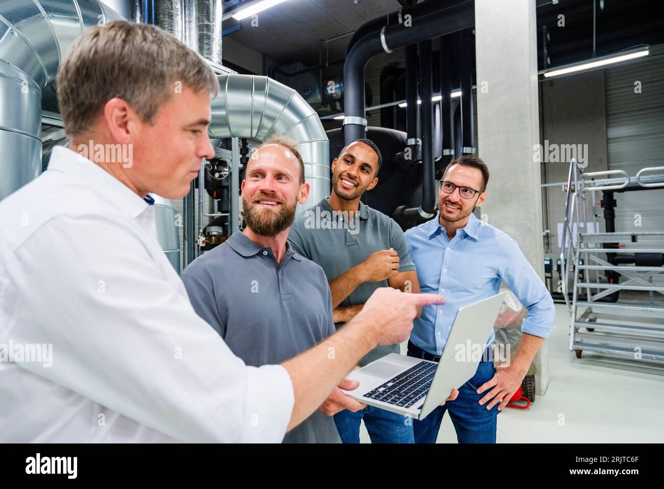 Businessmen and smiling employees with laptop having a meeting in ...