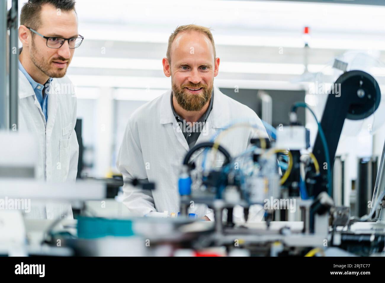 Colleagues in electronics factory watching machine work Stock Photo - Alamy