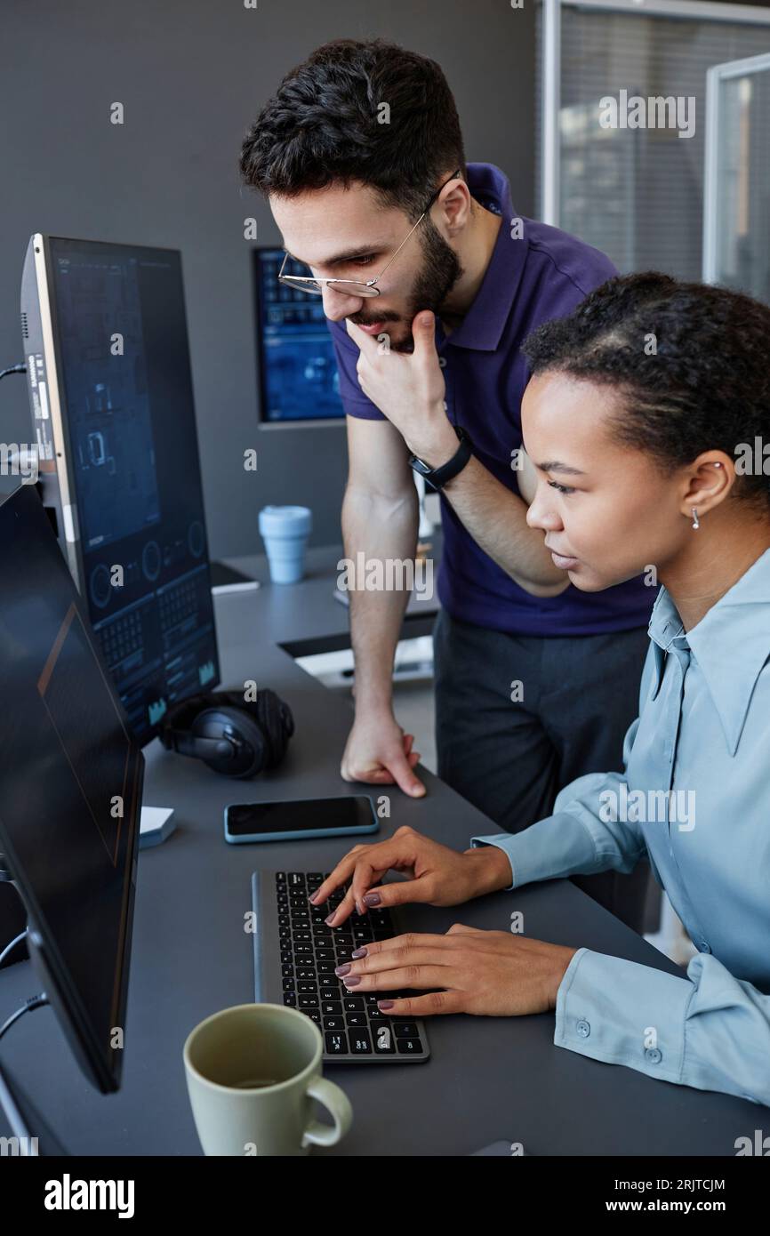 Young computer programmer with colleague typing on keyboard at desk Stock Photo - Alamy
