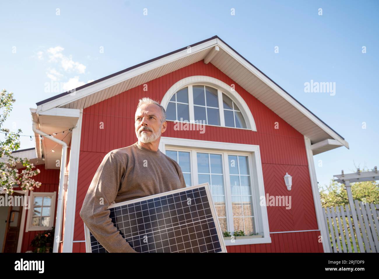 Man holding solar panel standing in front of house Stock Photo - Alamy