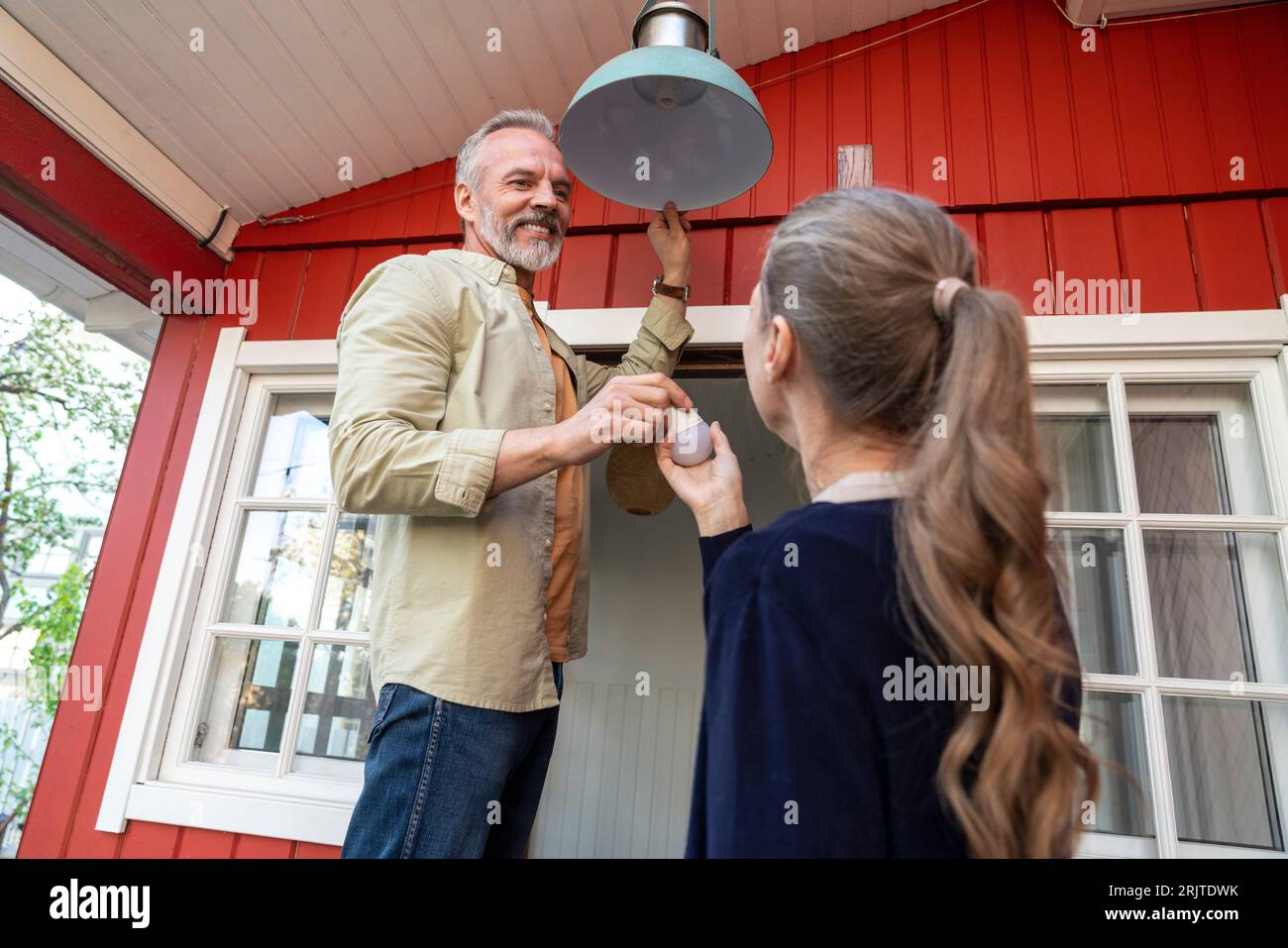 Woman helping man changing light bulb outside house Stock Photo - Alamy