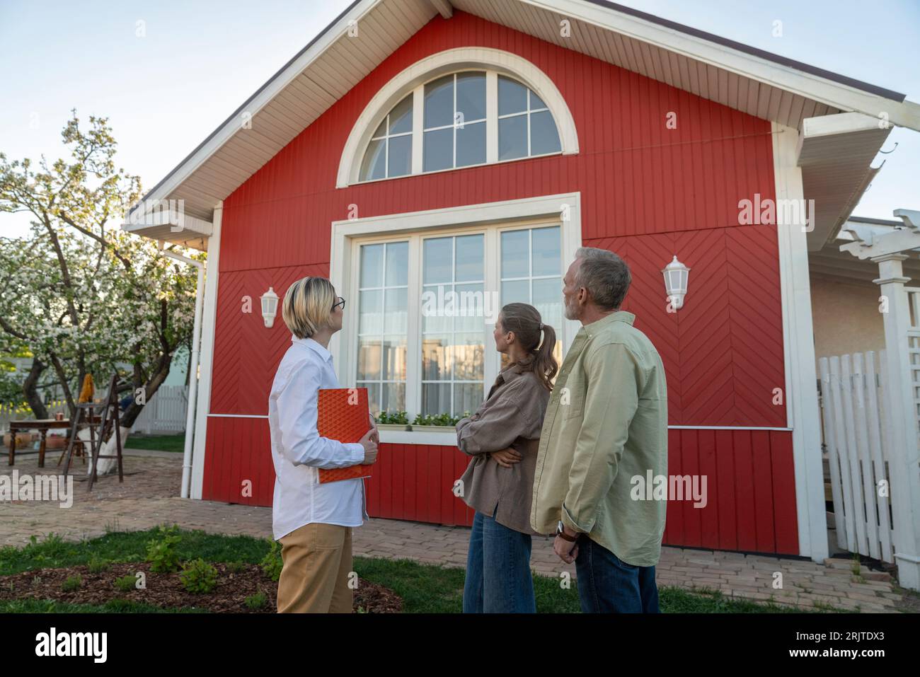 Real estate agent and couple looking at house Stock Photo - Alamy