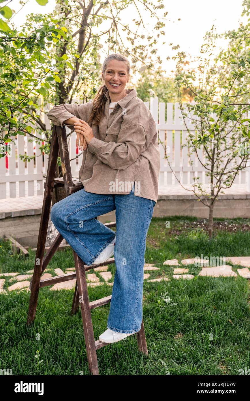 Smiling mature woman standing on ladder Stock Photo - Alamy