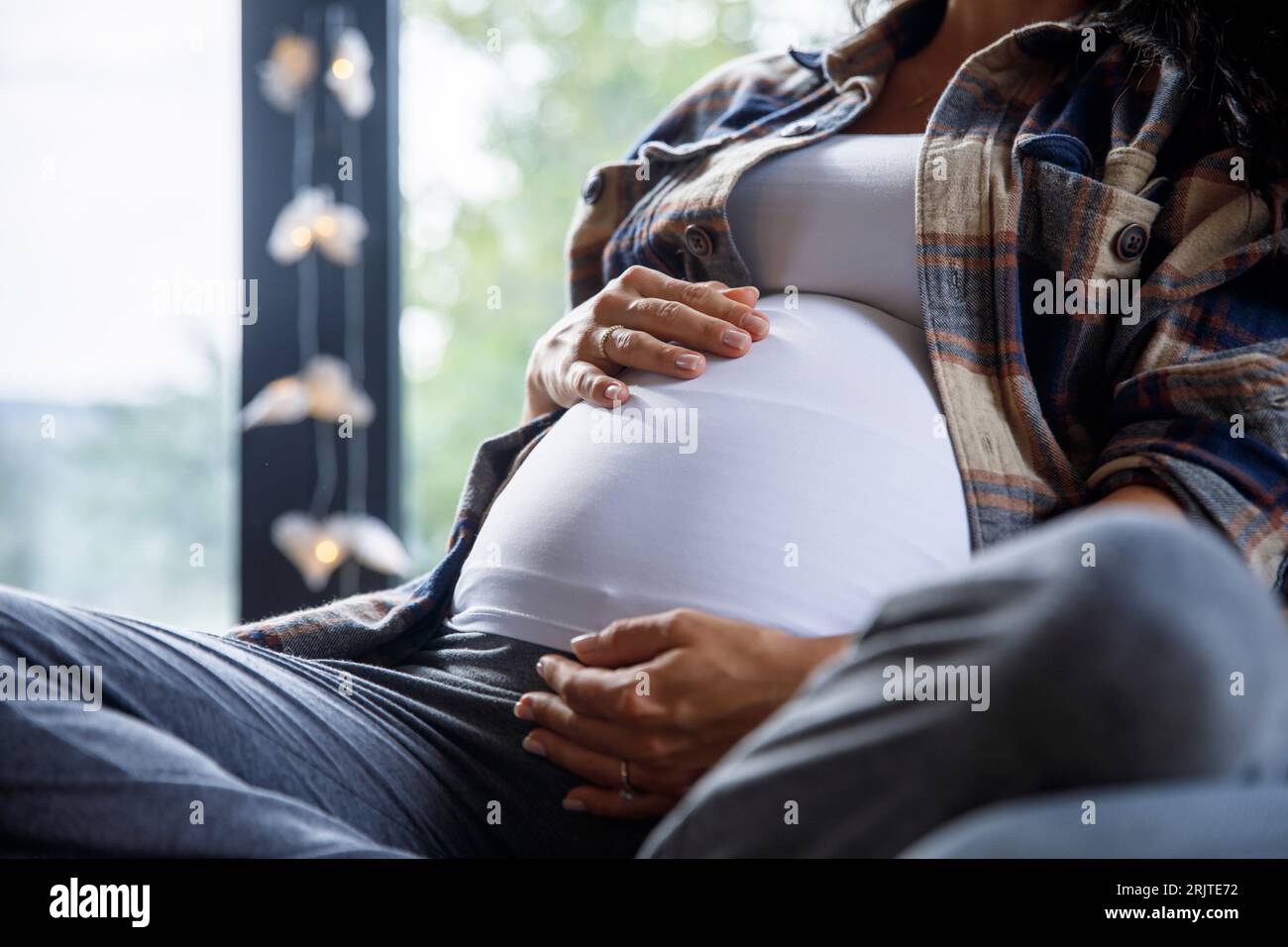 Pregnant woman with hands on stomach at home Stock Photo - Alamy