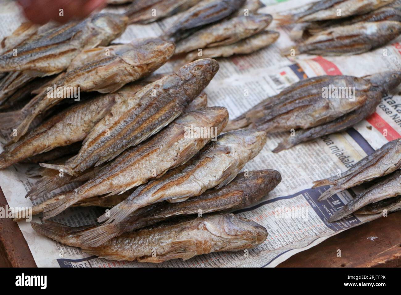 A pile of dried roasted fish displayed on newspaper sheets Stock Photo ...