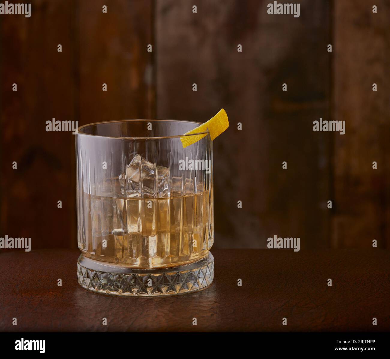 Whisky sour with ice garnished with lemon shot in a rustic setting ...