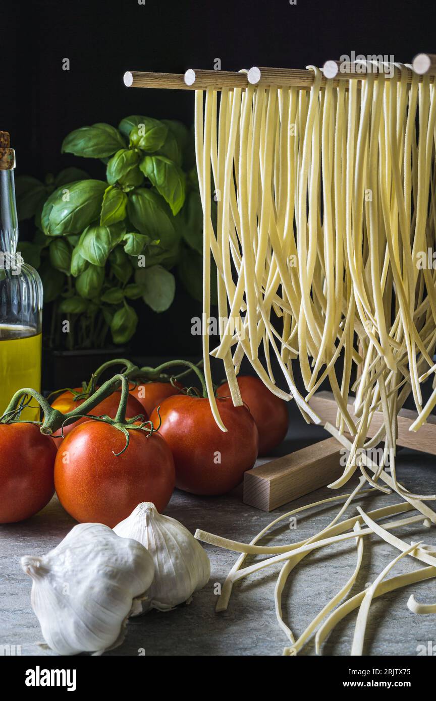 Fresh linguine pasta drying on a wooden rack. Portrait format, close up ...