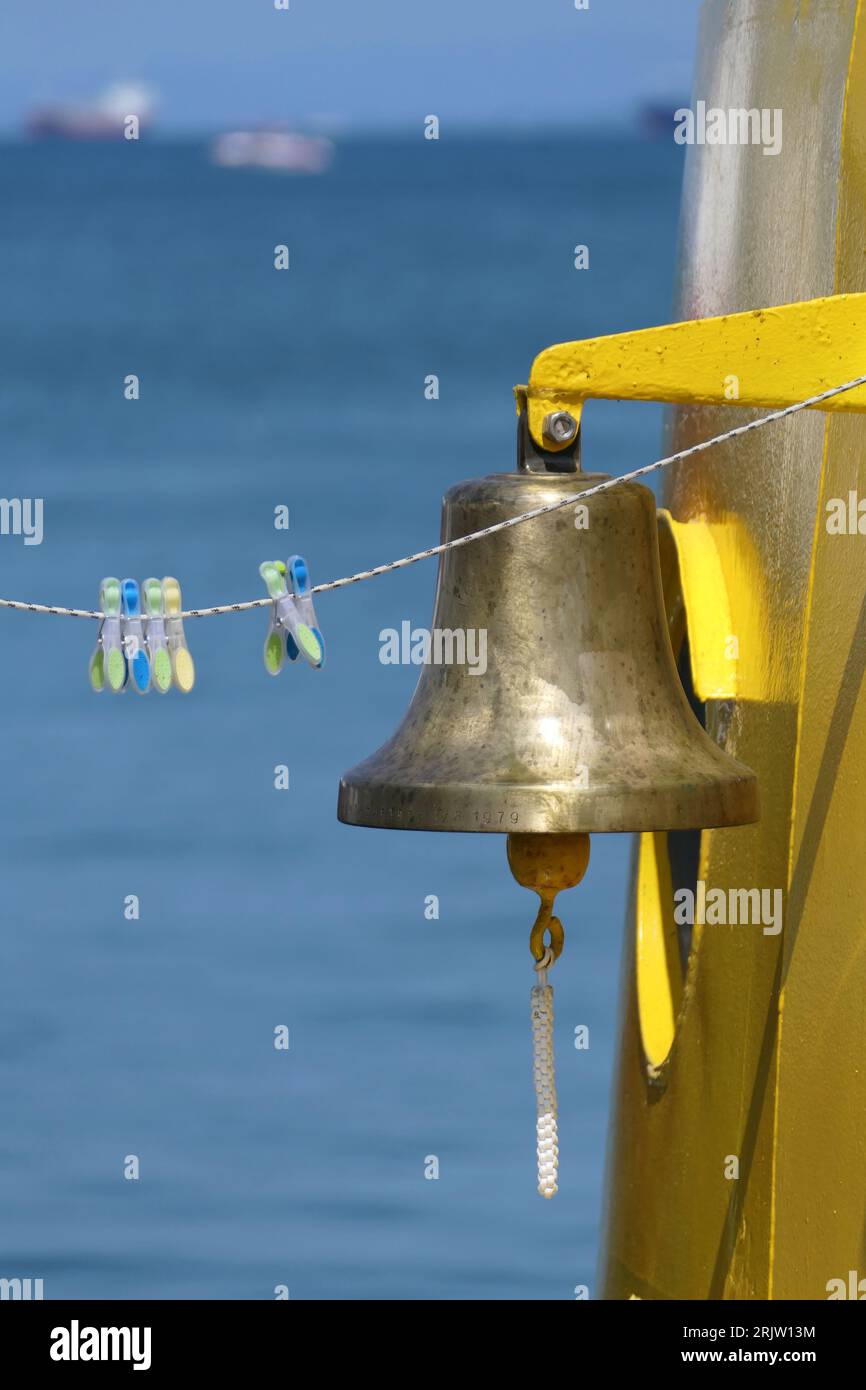 Bell on the deck of a ship with clothespins on a rope Stock Photo - Alamy
