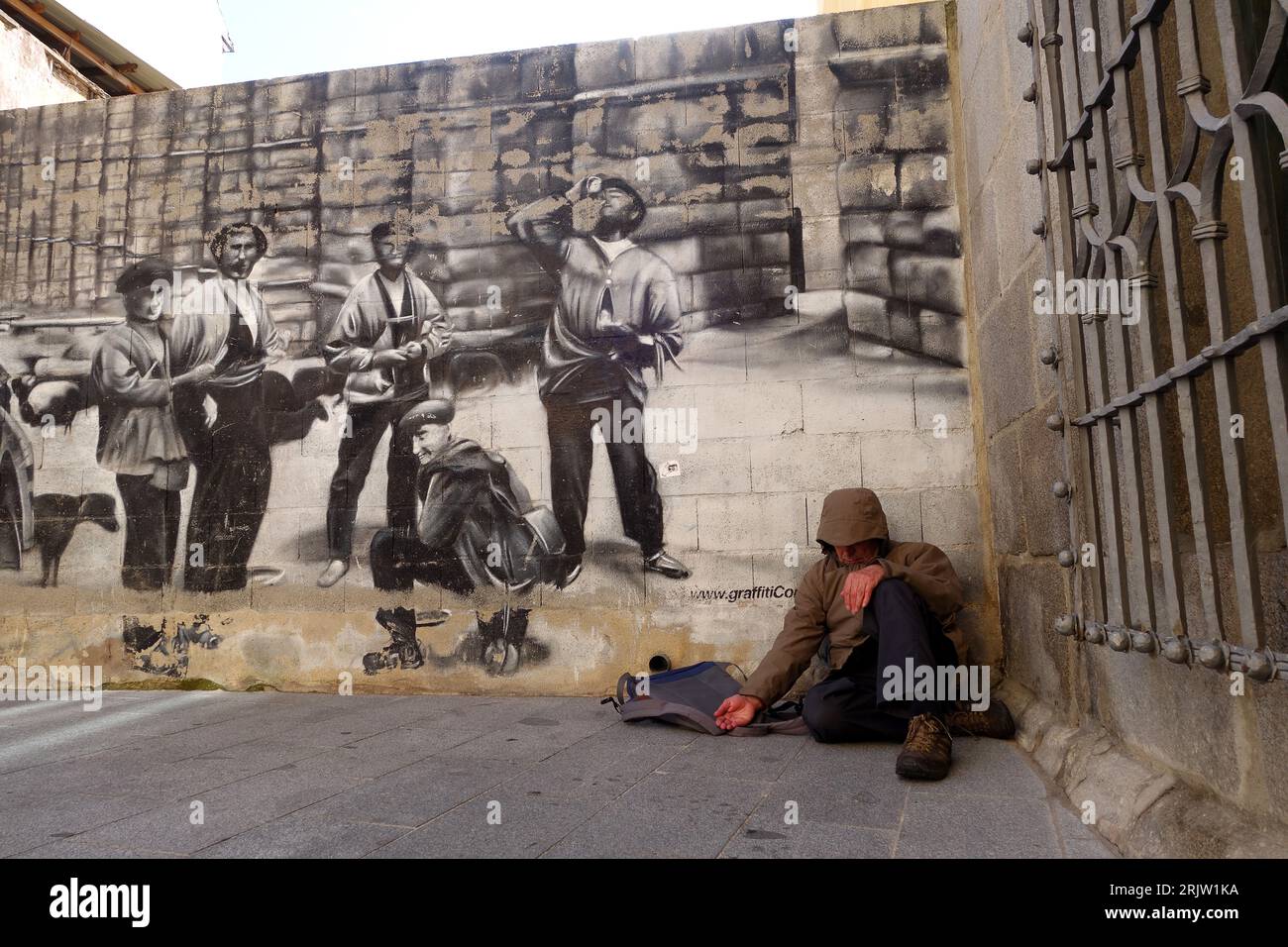 Man begging on the streets next to Street art graffiti in Segovia Stock ...