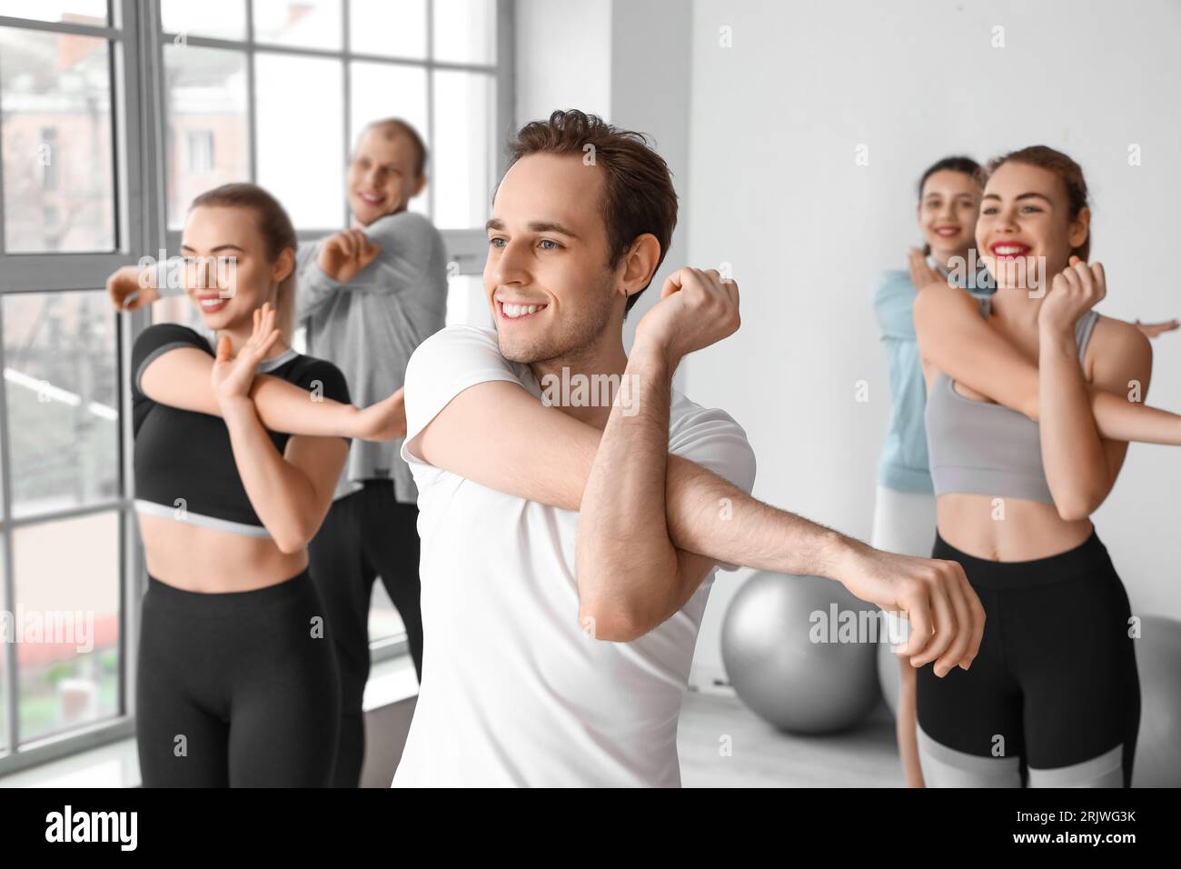 Sporty young man training with group in gym Stock Photo - Alamy