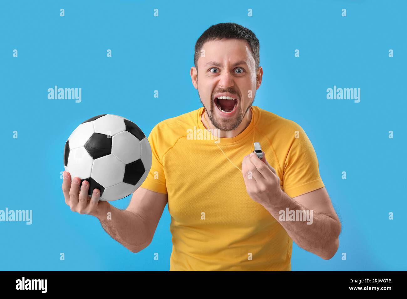 Angry male coach with soccer ball and whistle on blue background Stock ...