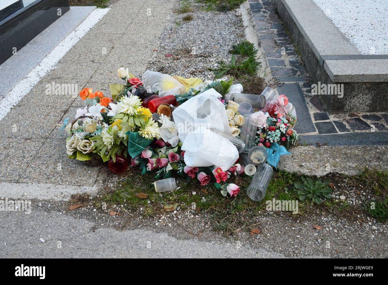 Cemetery waste and garbage. Piled up rubbish left strewn next to graves ...