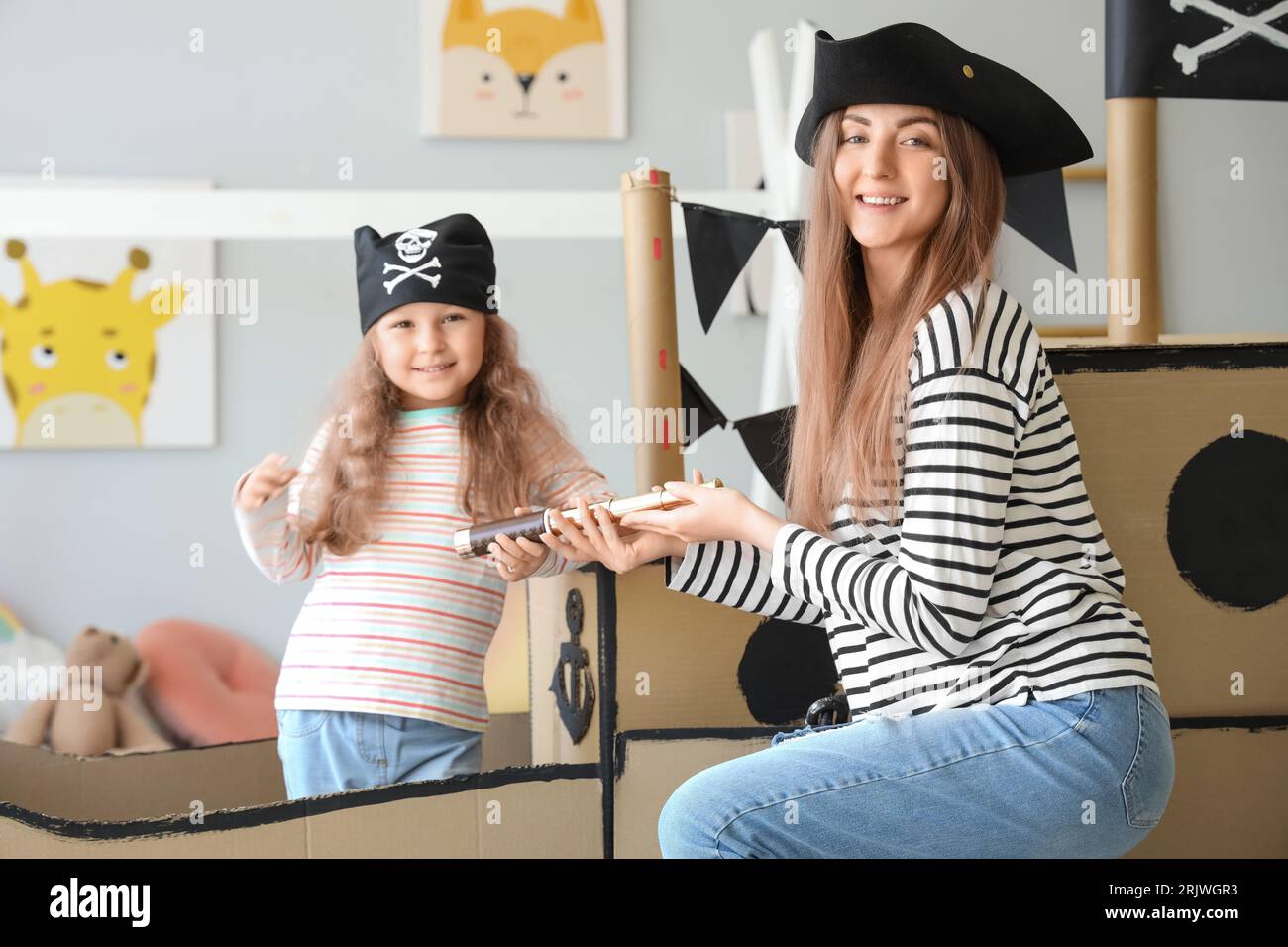 Cute little girl with her mother dressed as pirates playing at home ...