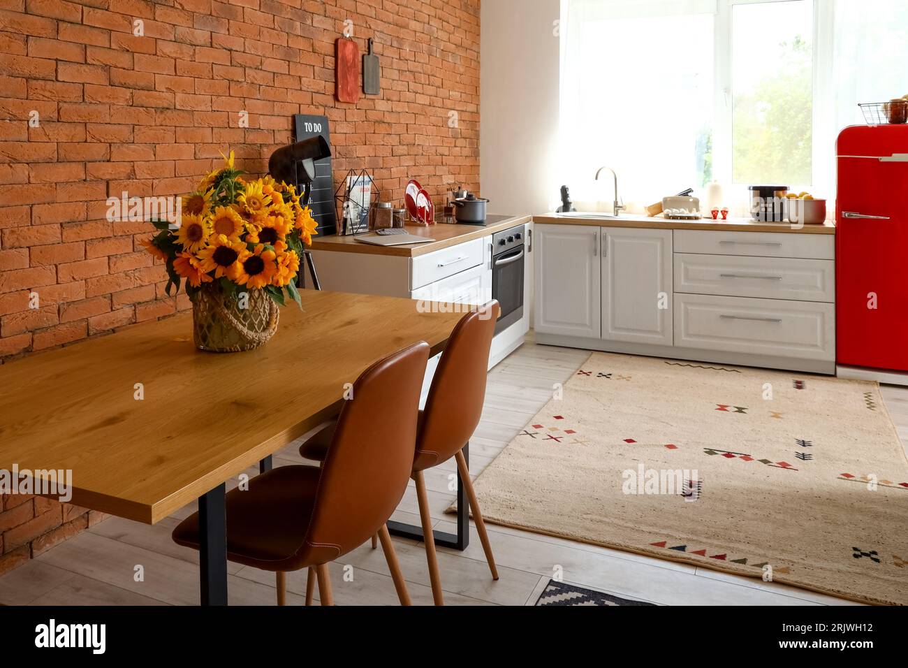Interior of modern kitchen with dining table, white counters and red ...