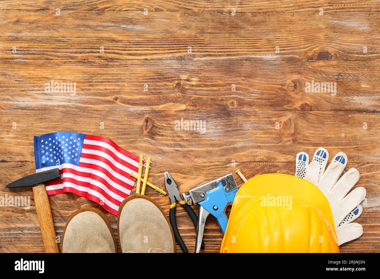 Different tools, hardhat, boots and USA flag on wooden background ...
