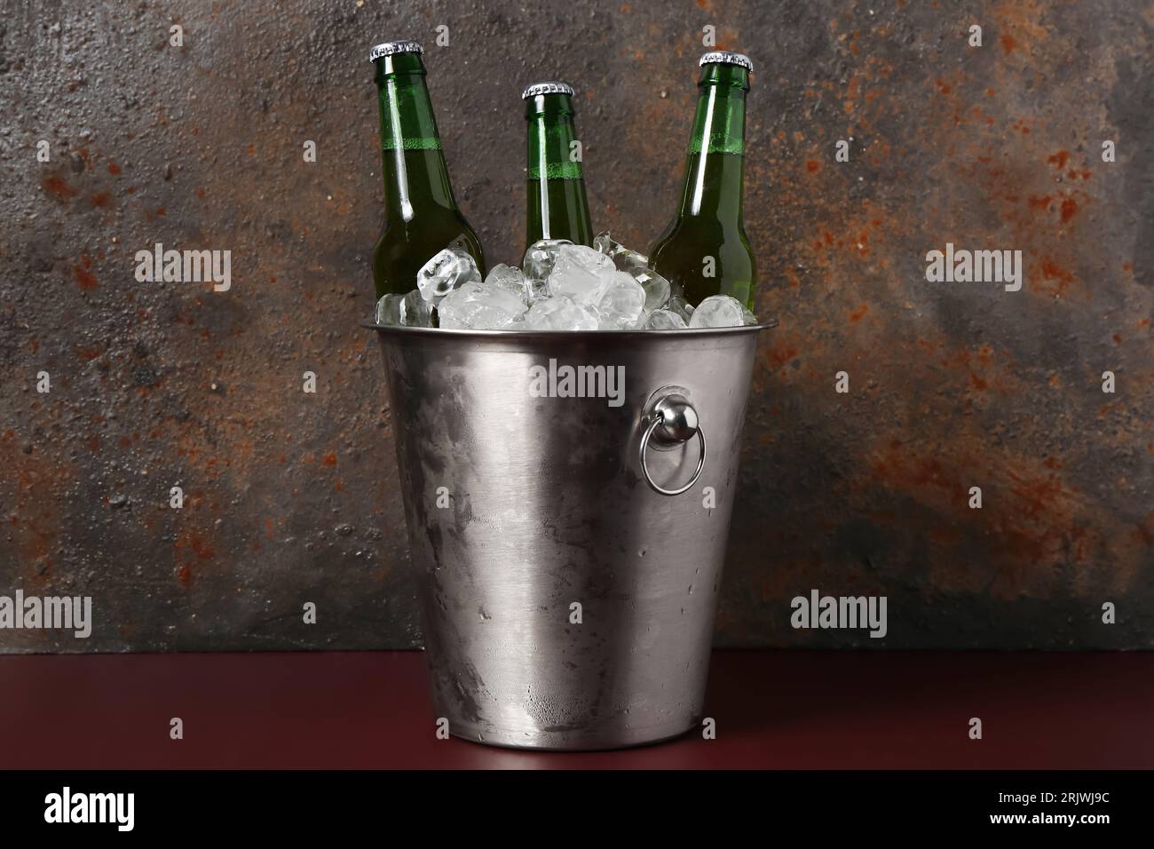Bucket with bottles of cold beer and ice cubes on red table Stock Photo ...