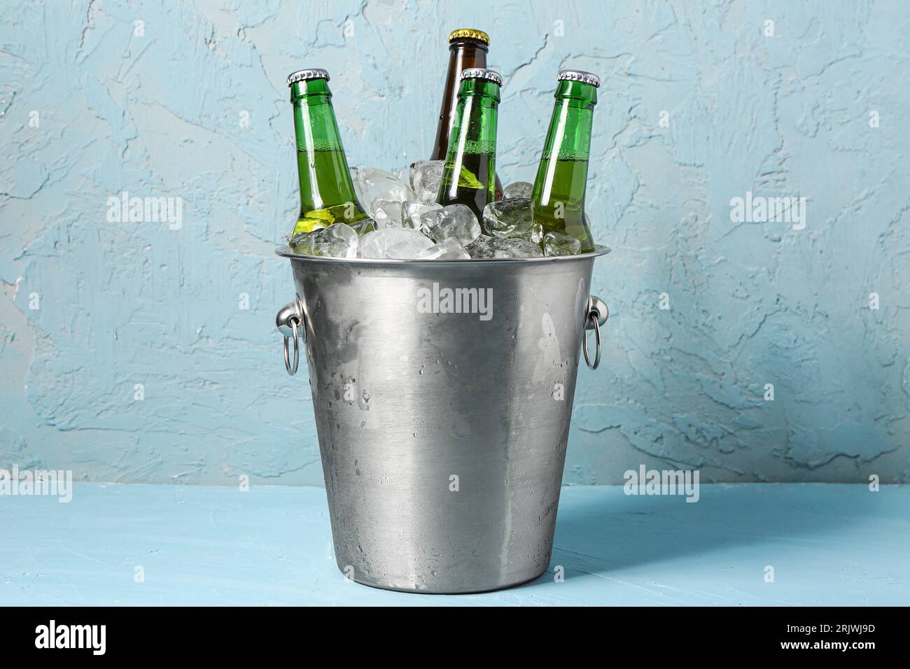 Bucket with bottles of cold beer and ice cubes on blue background Stock ...