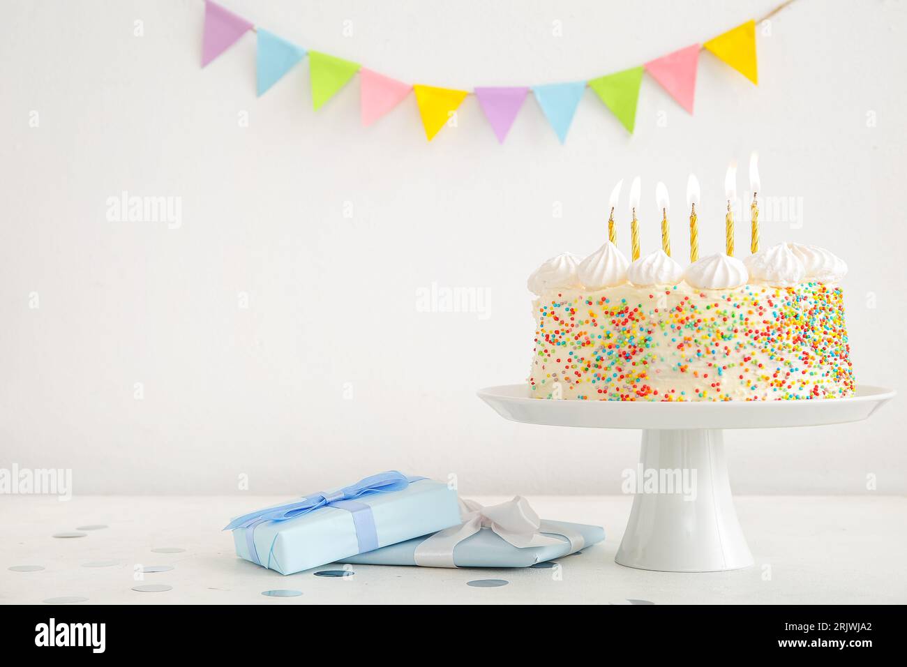 Stand with yummy cake and Birthday decorations on white table near wall ...