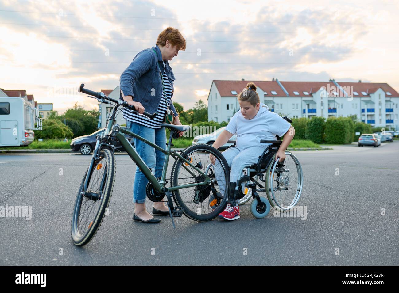 Boy transfers from wheelchair to bicycle, mother helping child to ...