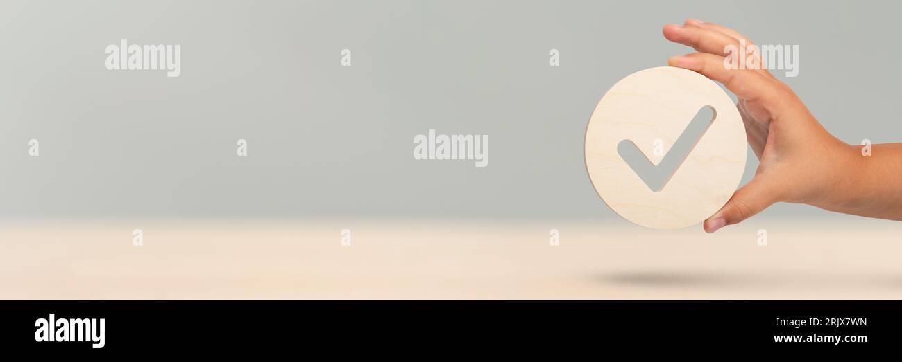 Hand holding check mark icon, banner with wooden check mark icon in ...