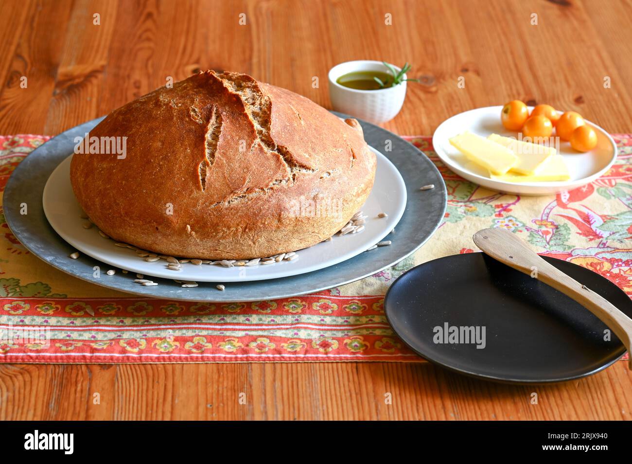 A freshly baked whole grain loaf of bread on a plate on the dining ...