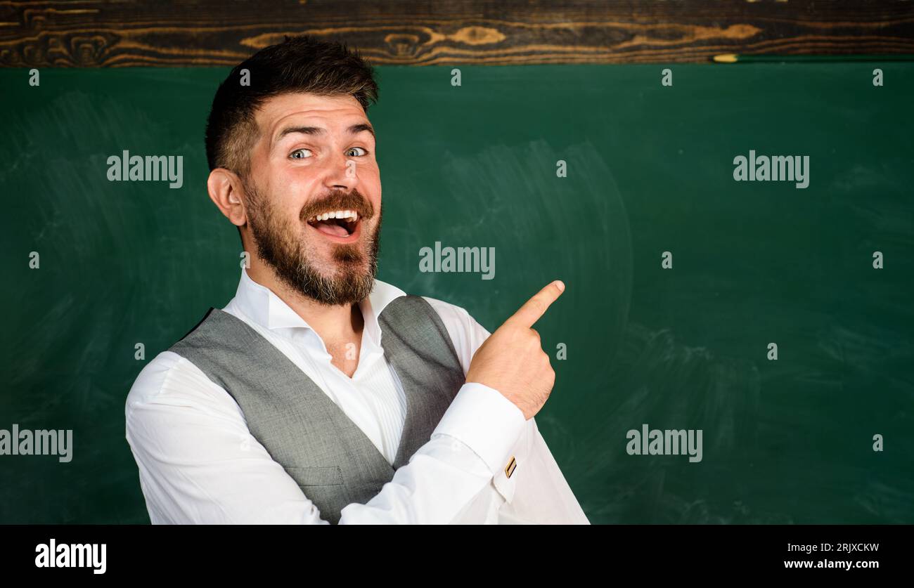 Happy university teacher near chalkboard pointing at copy space. High ...