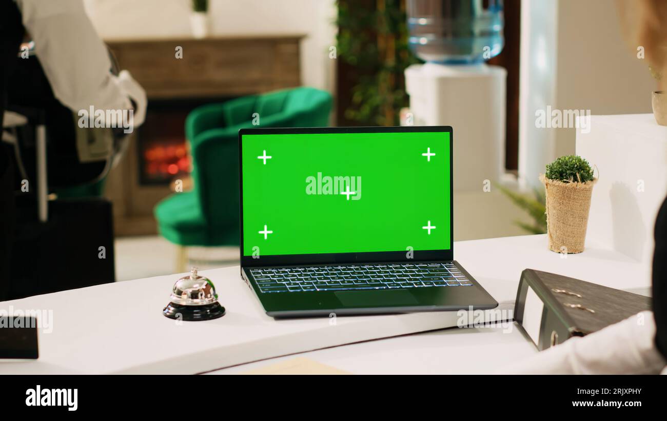 Hotel staff using greenscreen on laptop, working at front desk ...