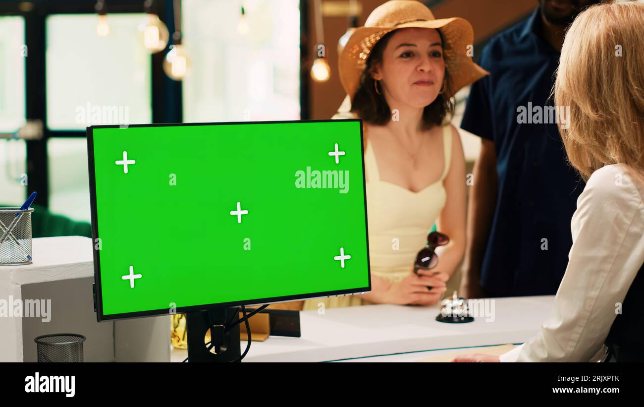 Employee working with greenscreen at hotel front desk, talking to ...