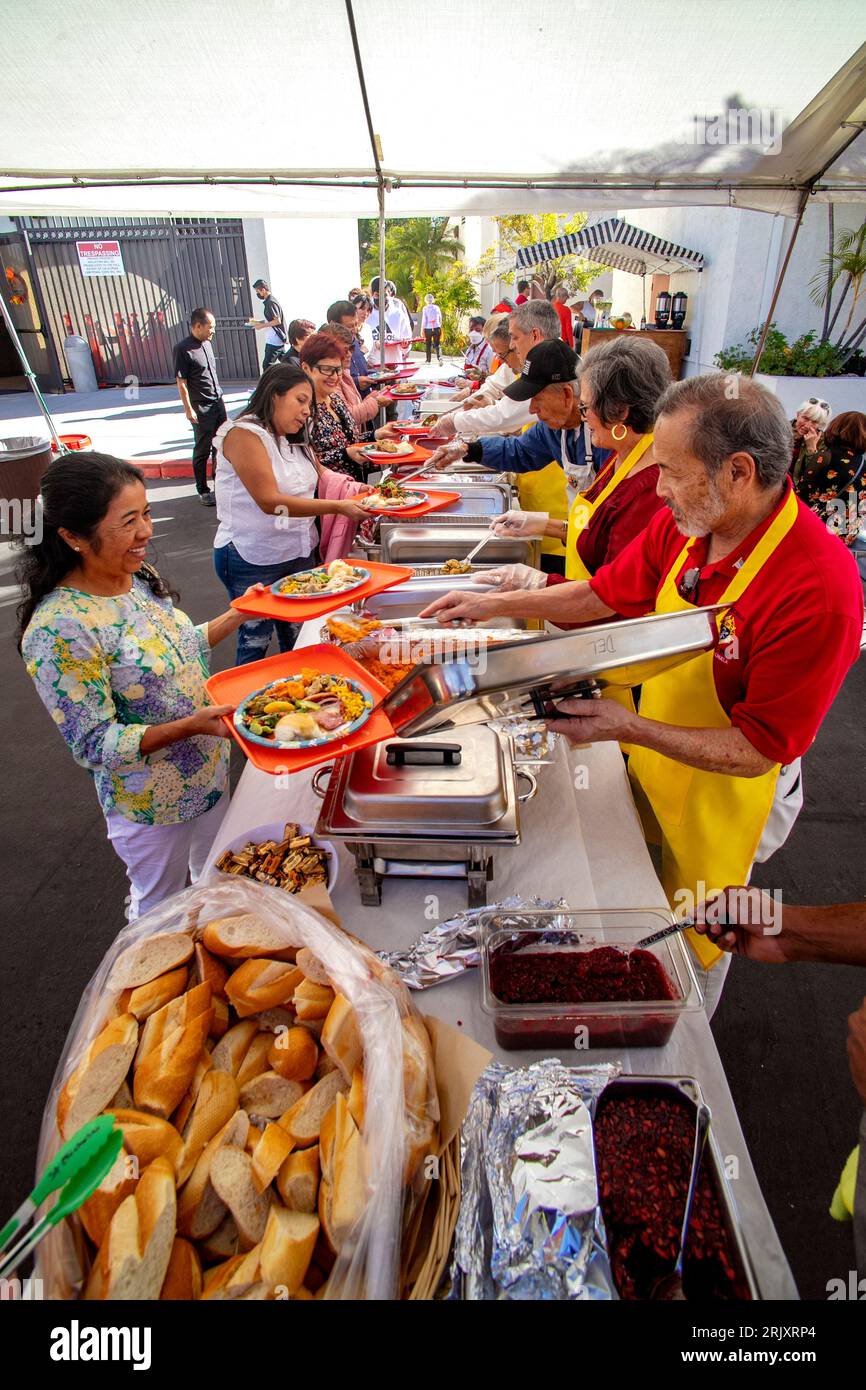 Multiracial volunteer servers feed guests at an outdoor Catholic church ...