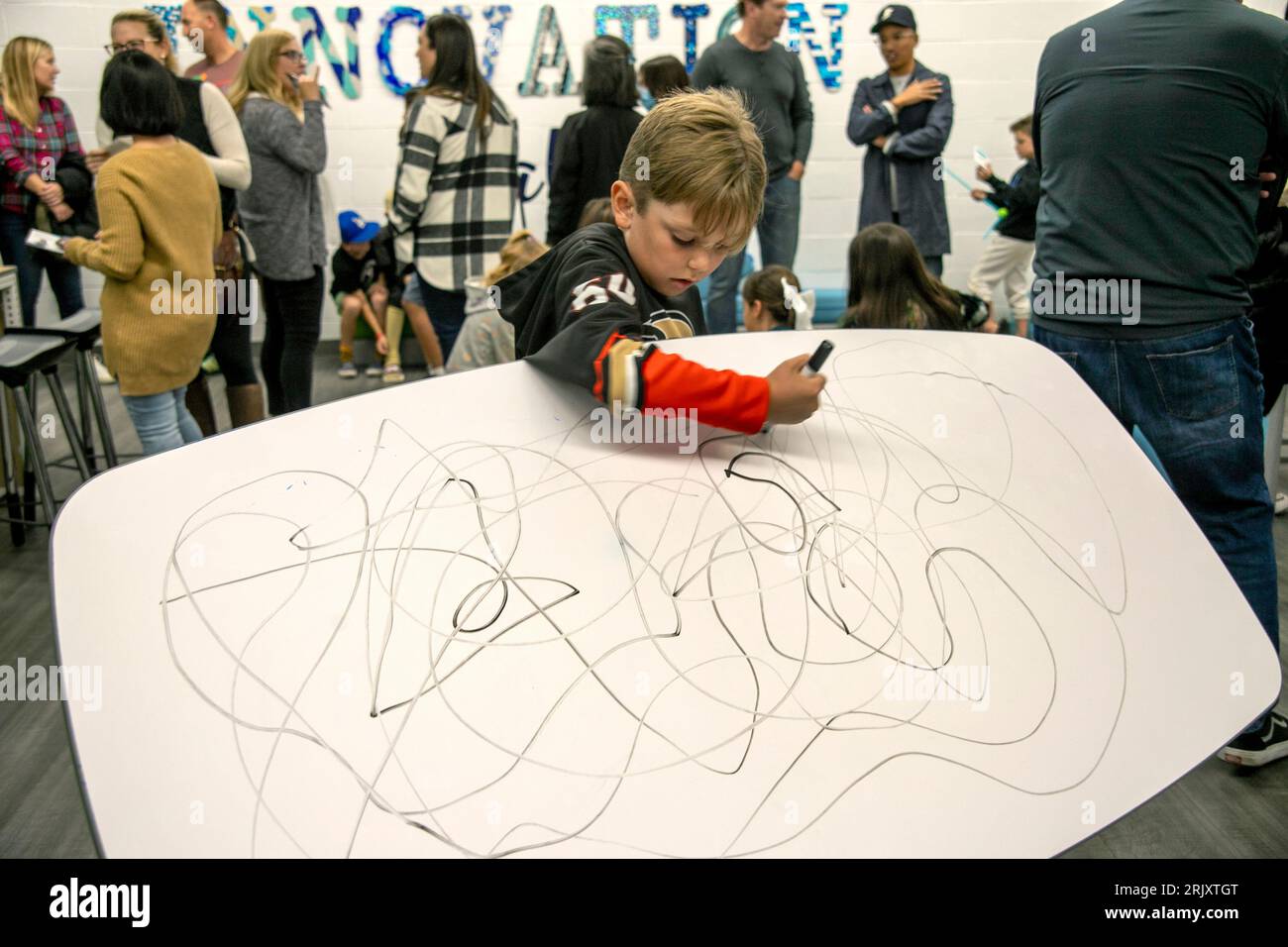 A boy scribbles on a table top at a technology-oriented "Innovation Lab" event at a Huntington ...