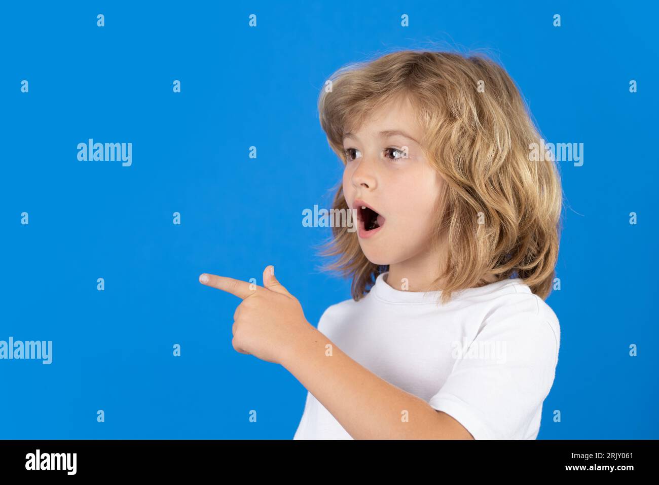 Surprised child looking away, pointing finger on isolated studio ...