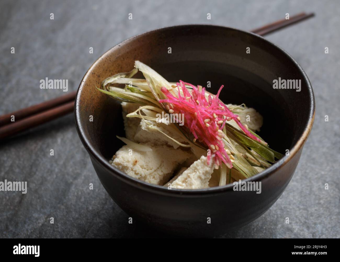 Japanese tofu in brown bowl topped with sliced myoga and ginger Stock ...