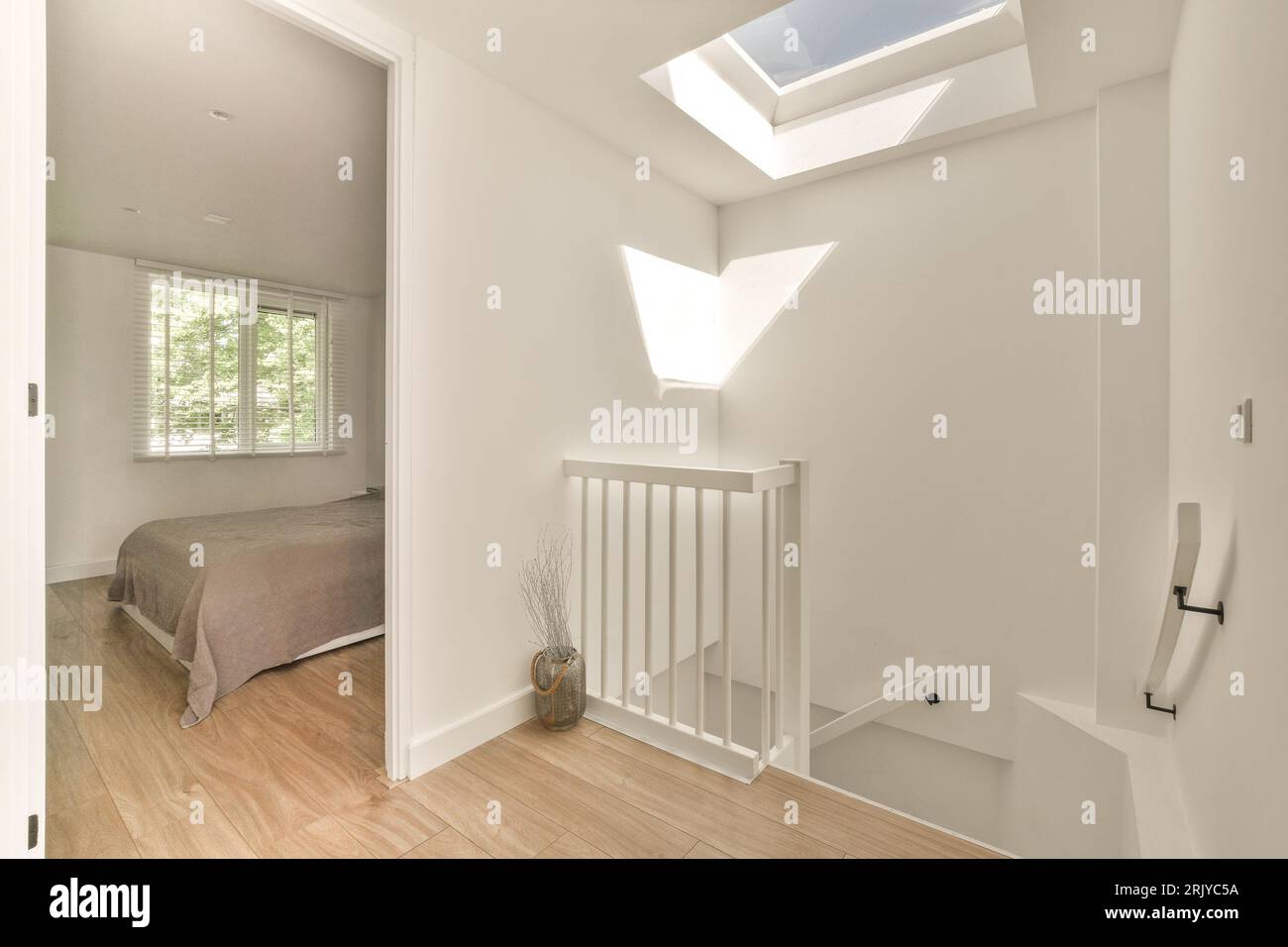 a bedroom with wood flooring and skylight above the bed in an attic ...