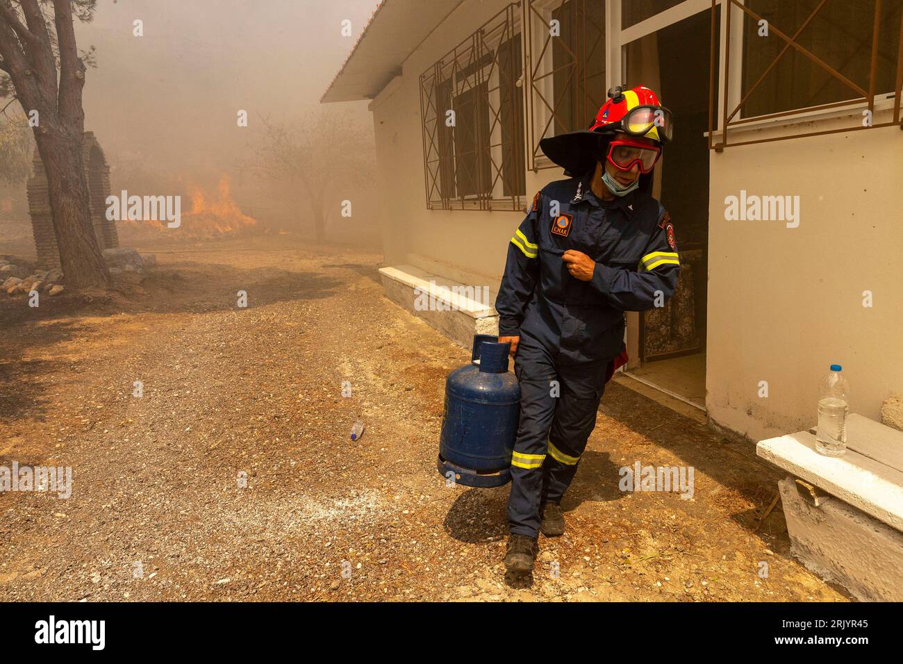 Athens, Greece. 23rd Aug, 2023. A firefighter removes a gas tank from a ...