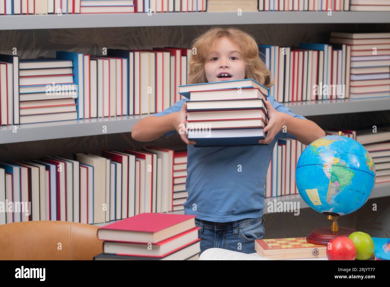 School boy with stack of books in library. Back to school. Funny little ...