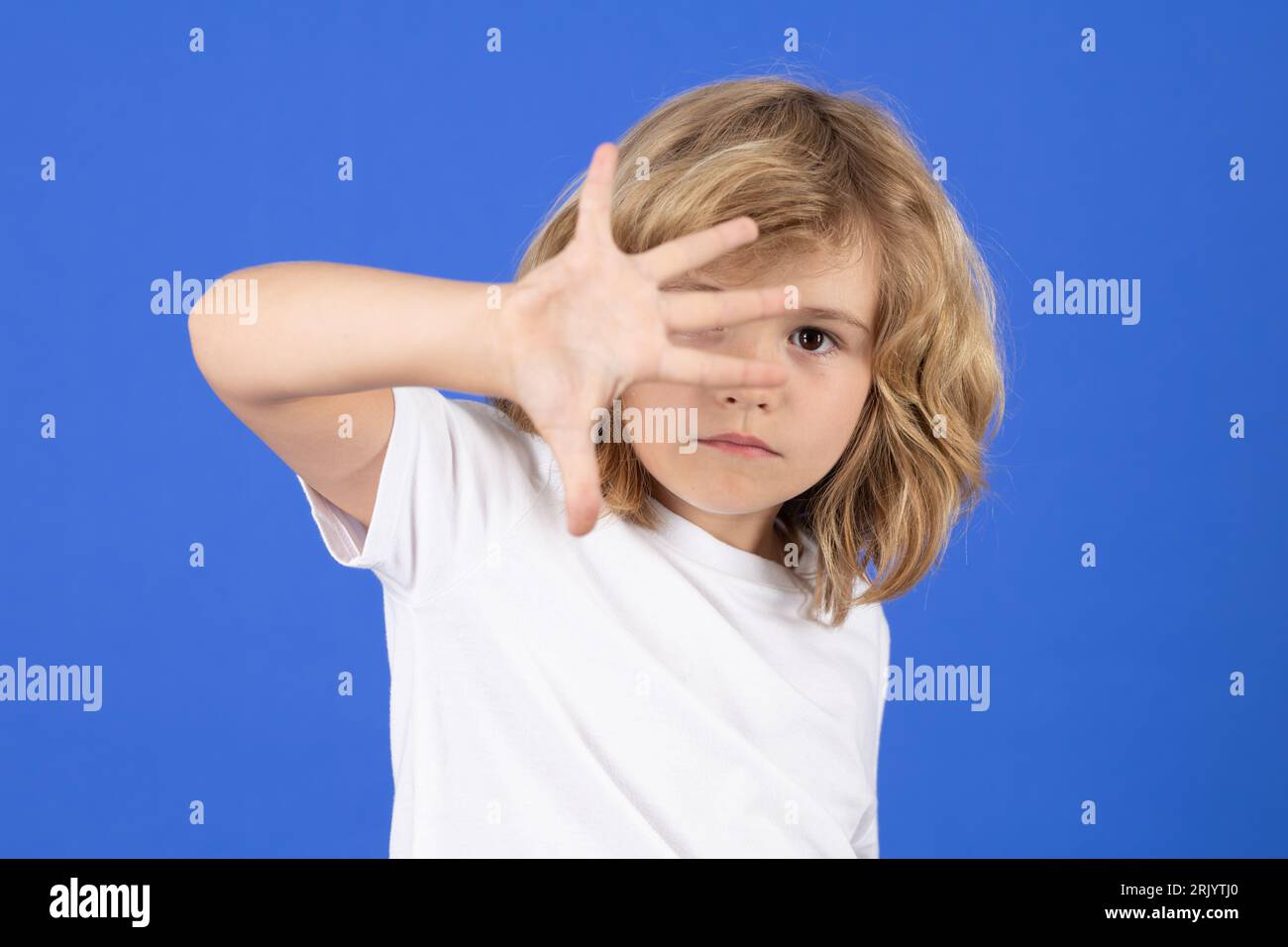 Child making stop gesture on isolated blue background. Kid showing ...