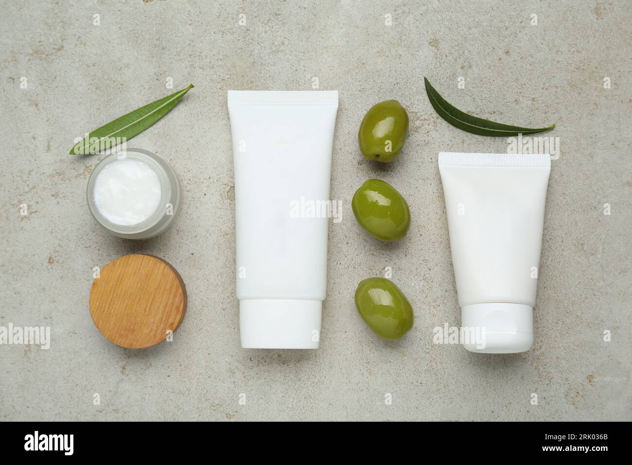 Cosmetic products with olive essential oil on light grey table, flat ...