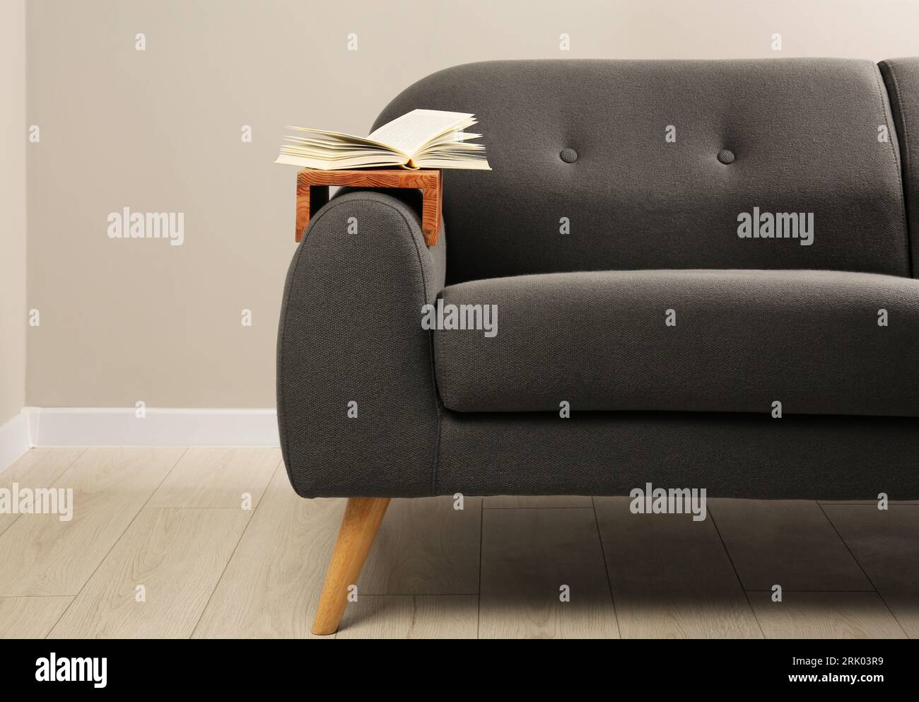 Open book on sofa with wooden armrest table in room. Interior element ...