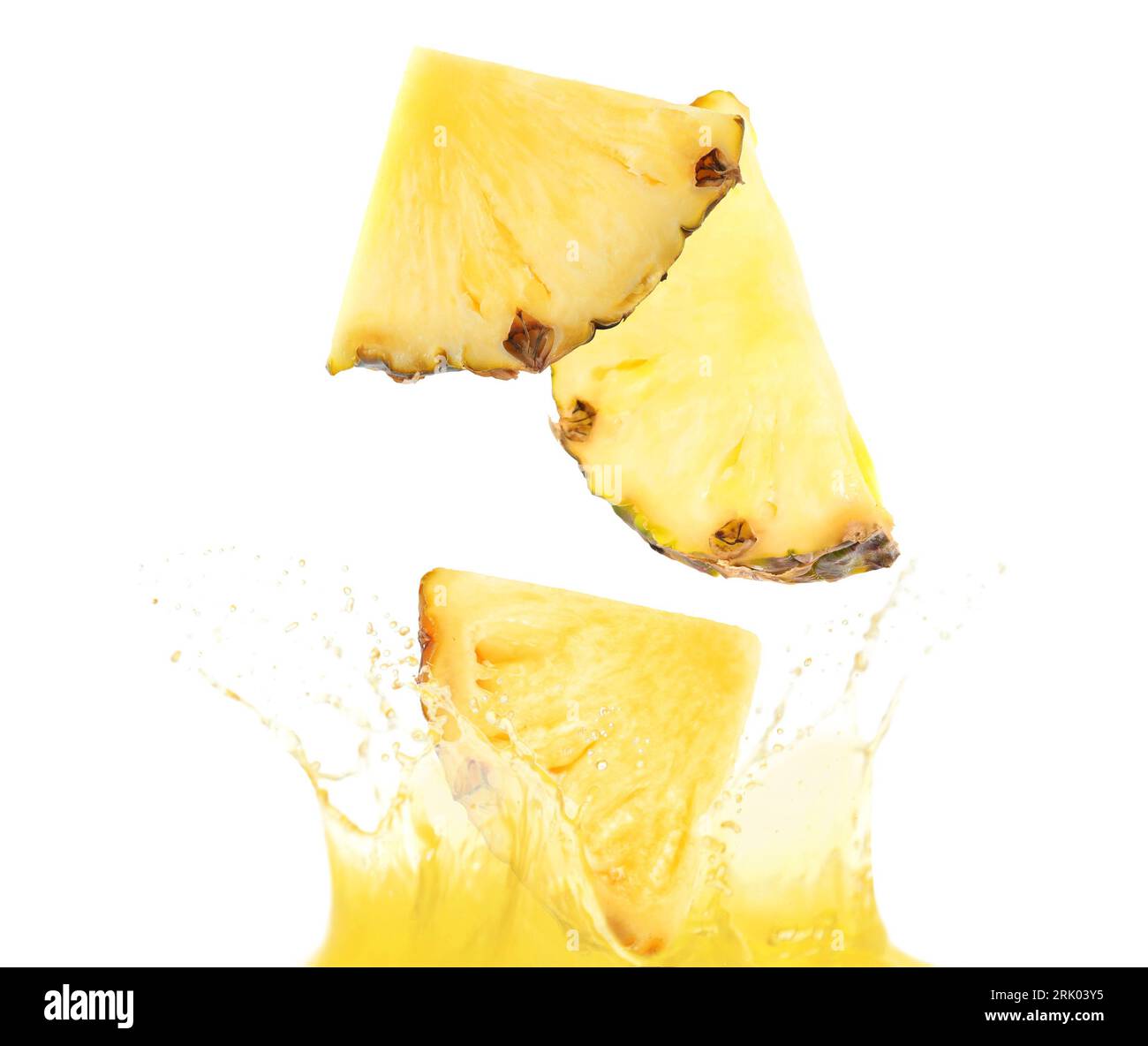 Cut pineapple falling into juice on white background Stock Photo - Alamy