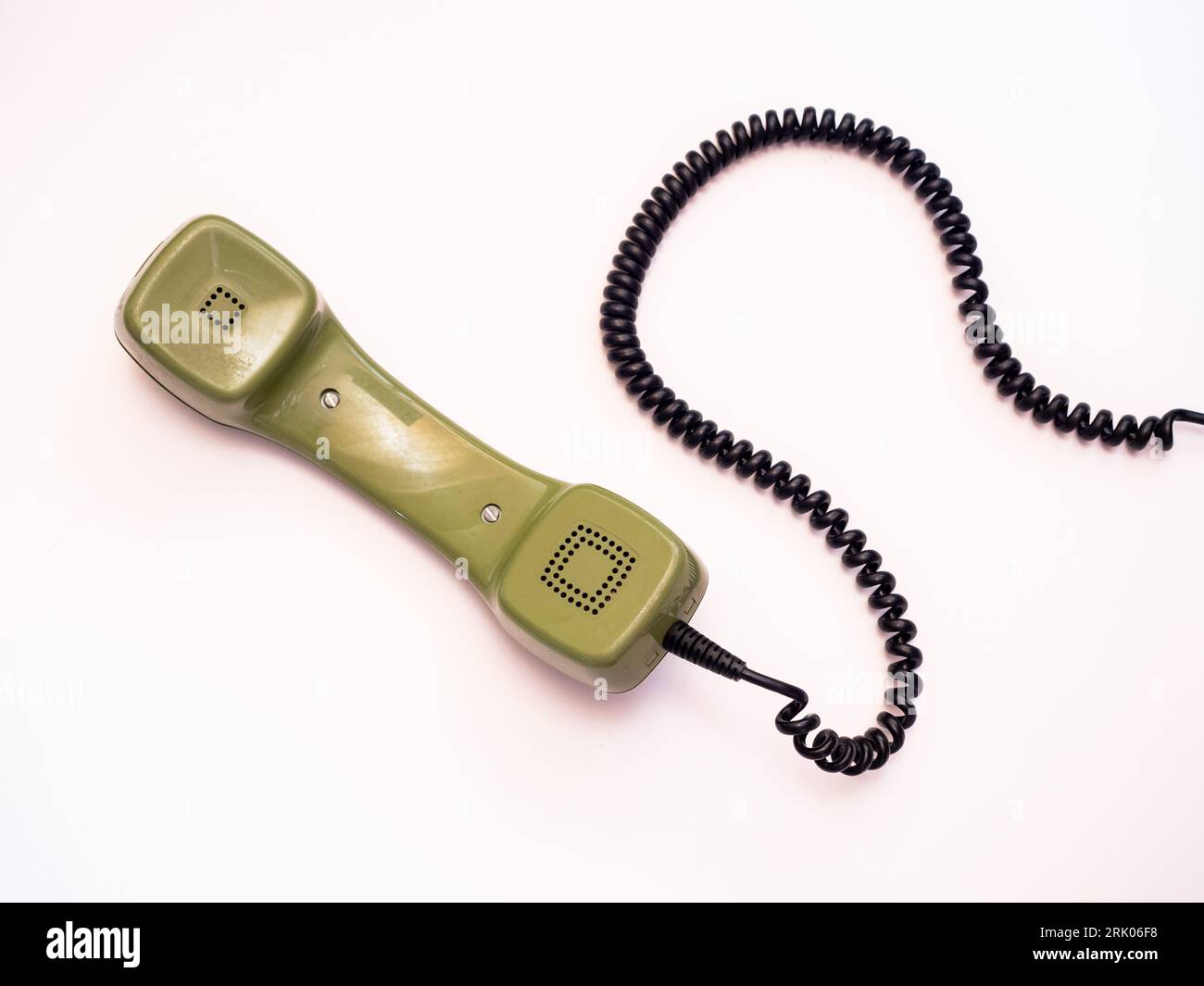 The handset of an old rotary phone lies on a white background. The ...