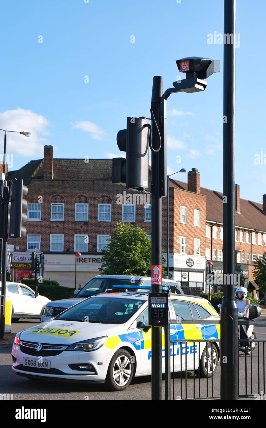 London, UK. A police car passes a Ulez camera covered with stickers ...