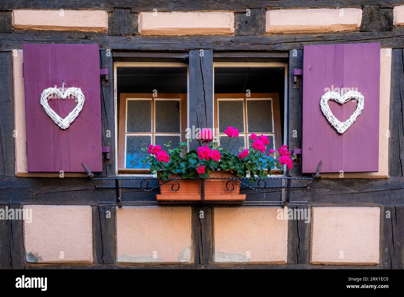 A close-up of a window with purple shutters and white hearts on it and ...