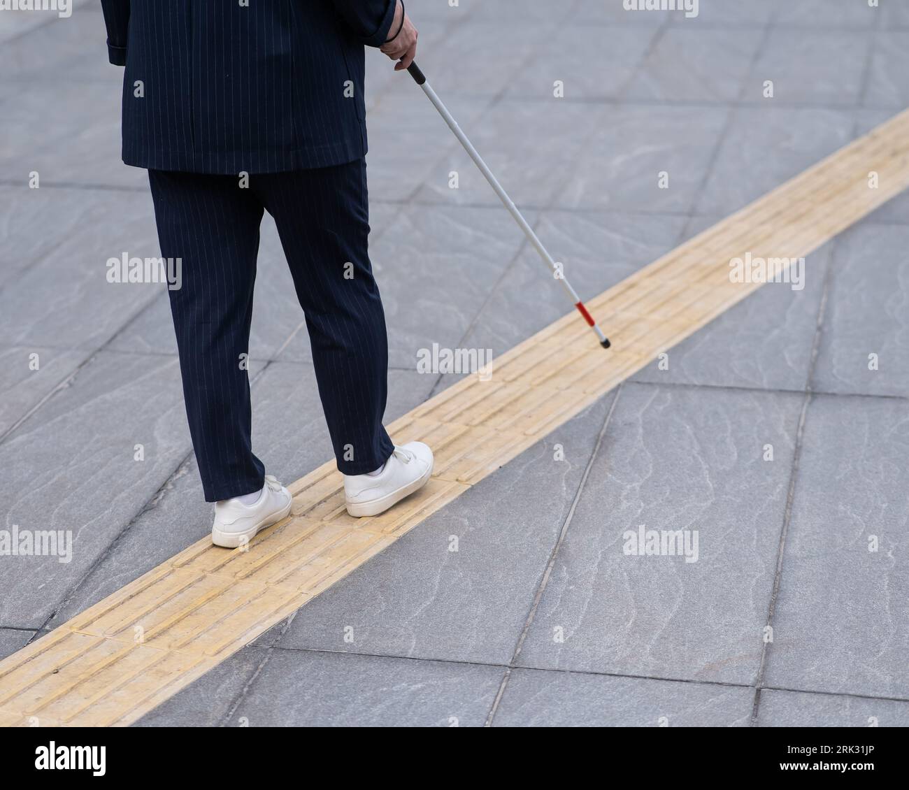 Close-up of the legs of a blind businesswoman walking along a tactile ...