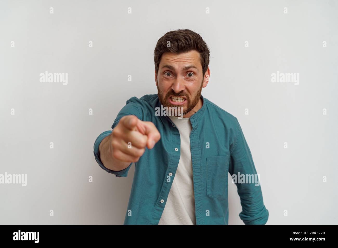 Indignant man standing over white background pointing displeased and ...