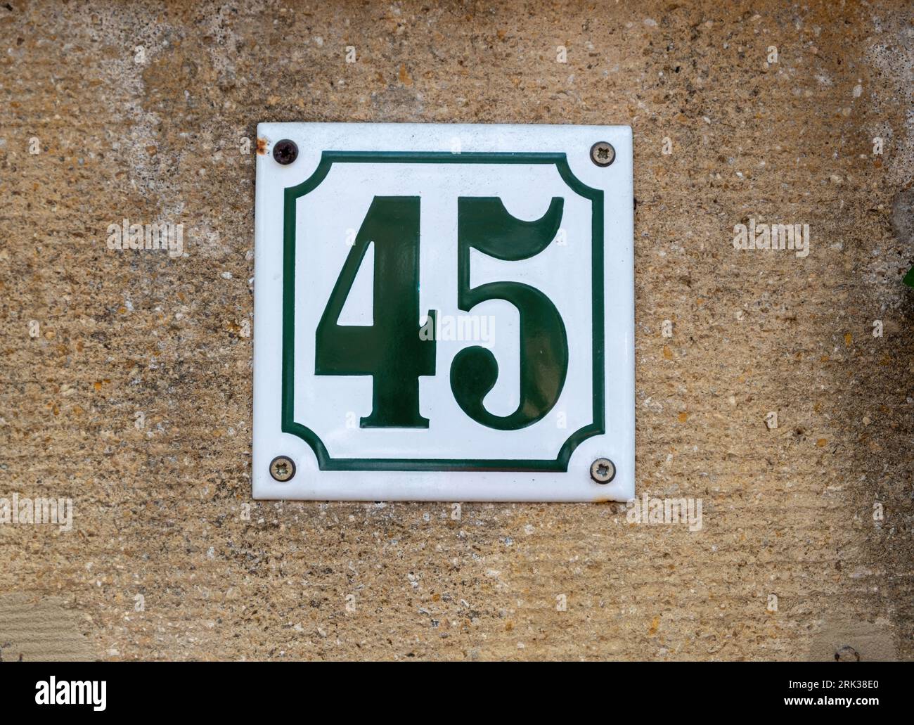 White metallic sign with black number digit 45 on rough brown plastered ...