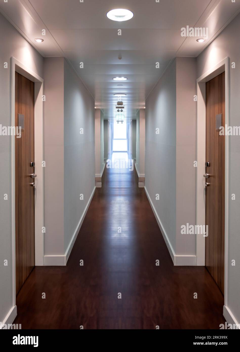 Empty illuminated hotel or office corridor with wooden floor. Luxury ...