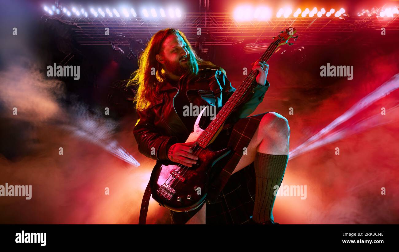 Rock and roll concert. Artistic, expressive man with long hair playing ...